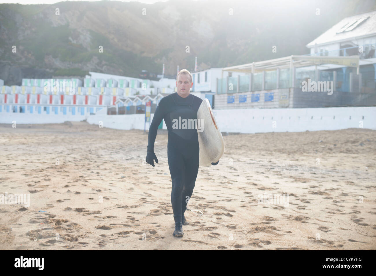 Surfer carrying board on beach Stock Photo - Alamy