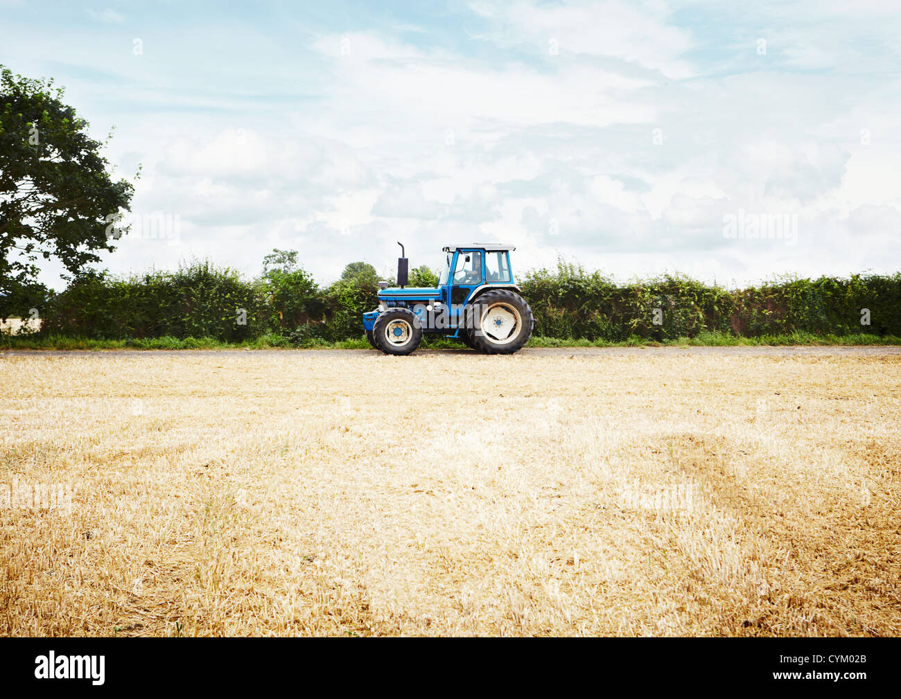 Tractor driving in tilled crop field Stock Photo - Alamy