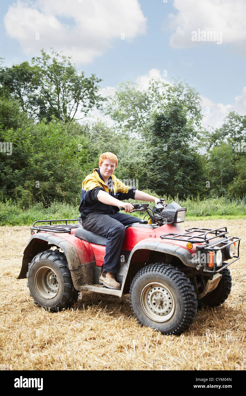 Worker driving four wheeler in field Stock Photo - Alamy