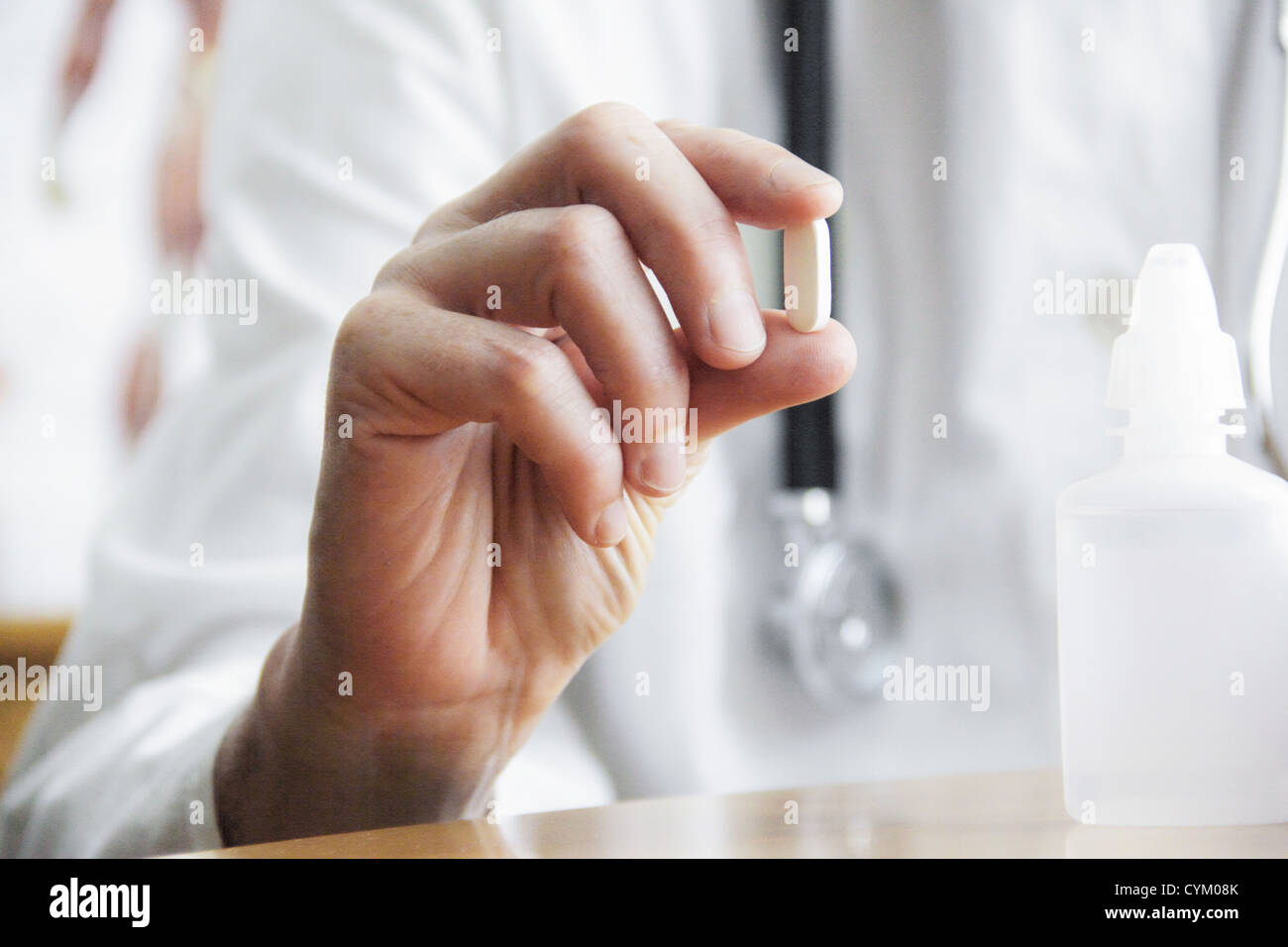 Doctor holding pill in office Stock Photo - Alamy