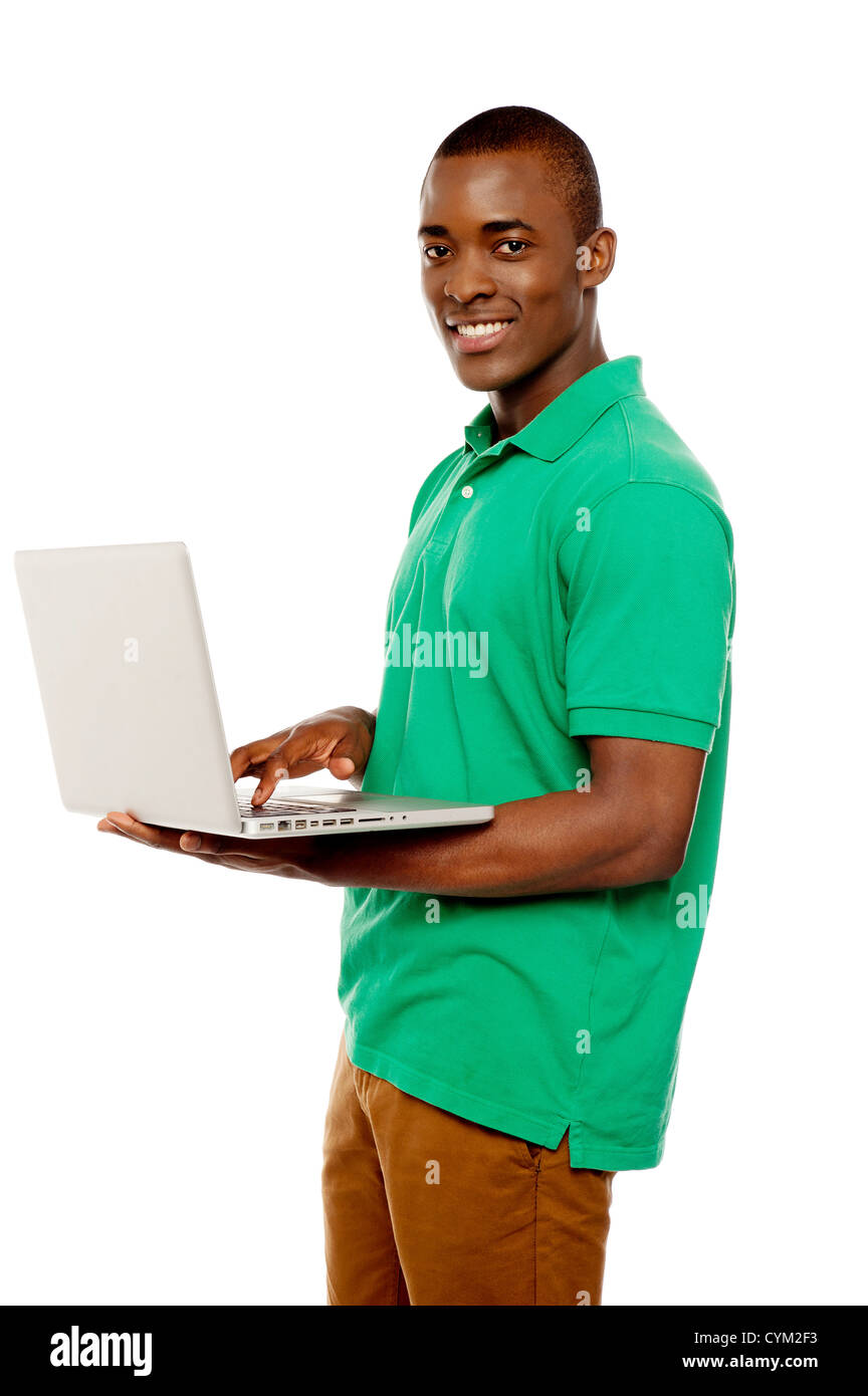 Cool teenage guy surfing internet on laptop and smiling at camera Stock ...