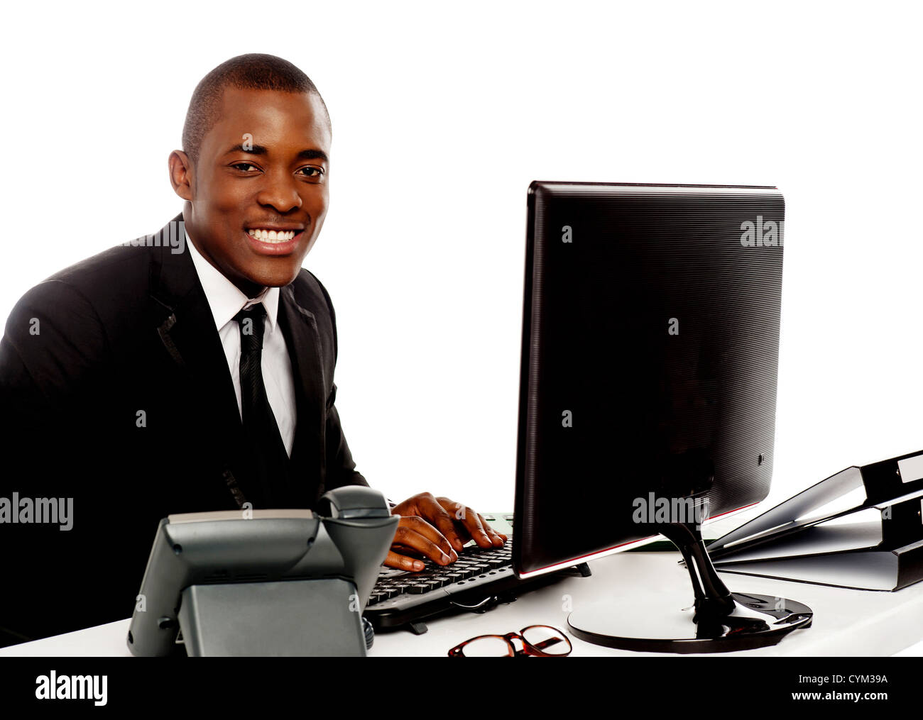 Smiling young corporate man using computer looking at camera Stock ...