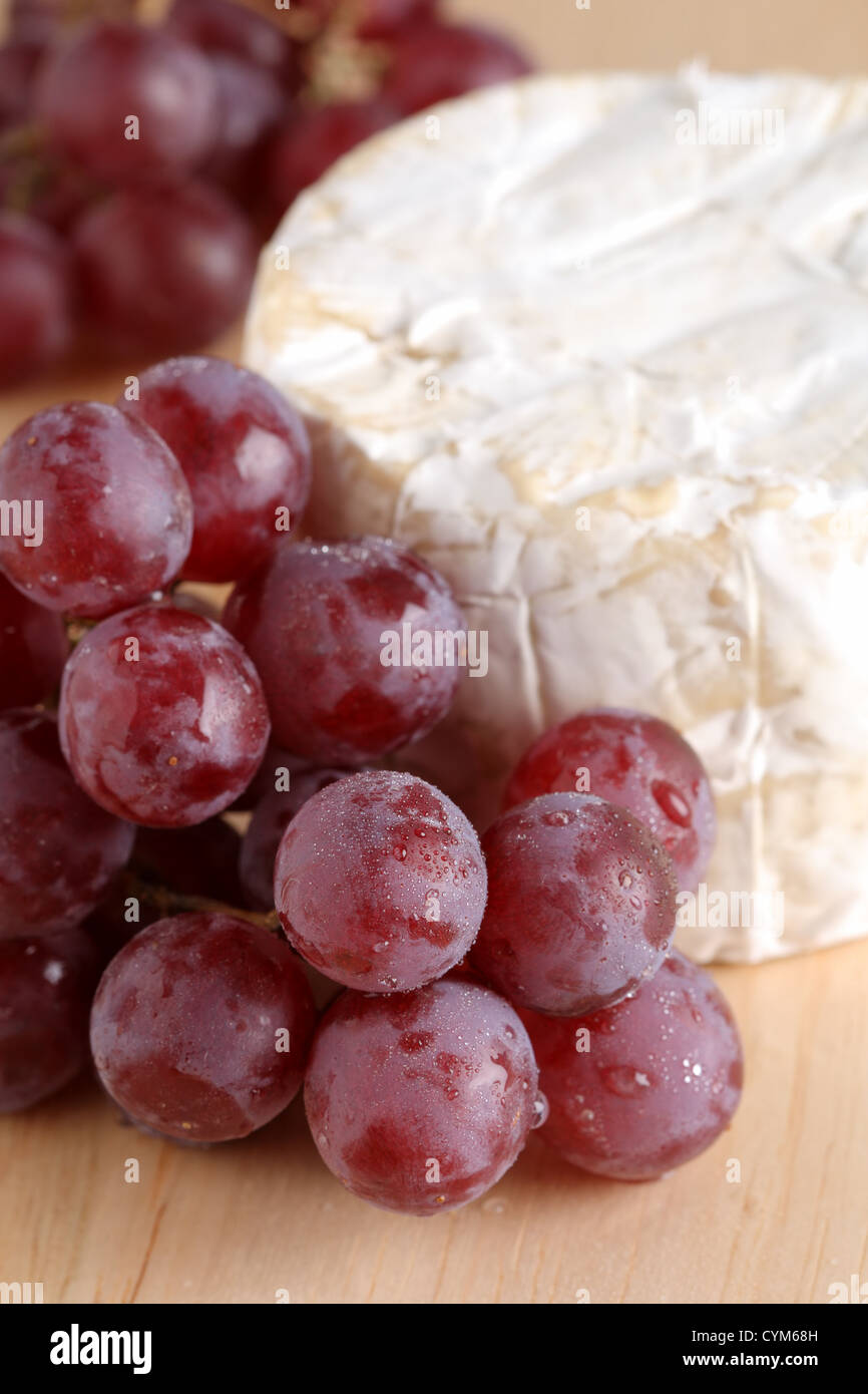 red grape and soft cheese on wood, shallow dof, focus on the grape ...