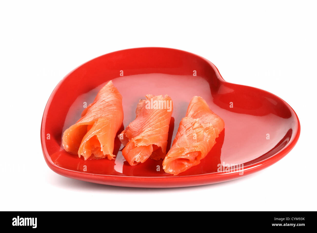 three pieces of smoked salmon on red heart shape plate, white ...
