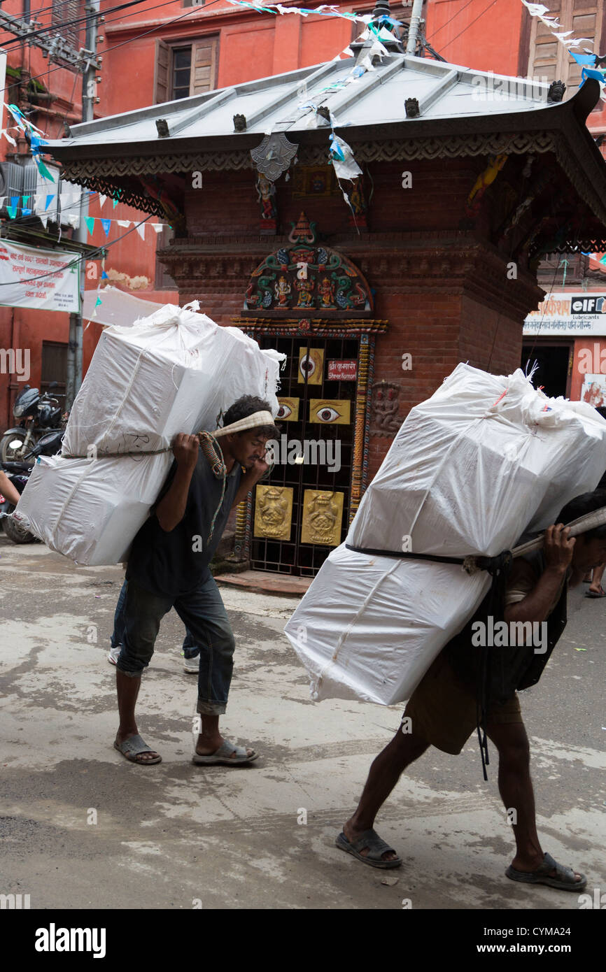 Two nepalese men carrying an heavy load on the back Stock Photo - Alamy
