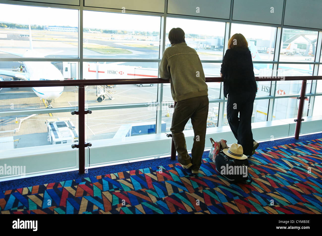 Two passengers look out of a window while waiting for a plane at ...