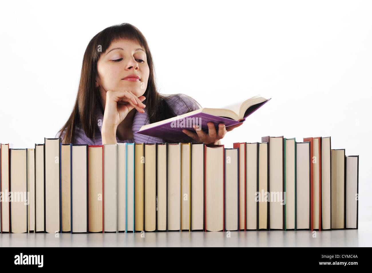 young woman reading a book behind a big pile of books Stock Photo - Alamy