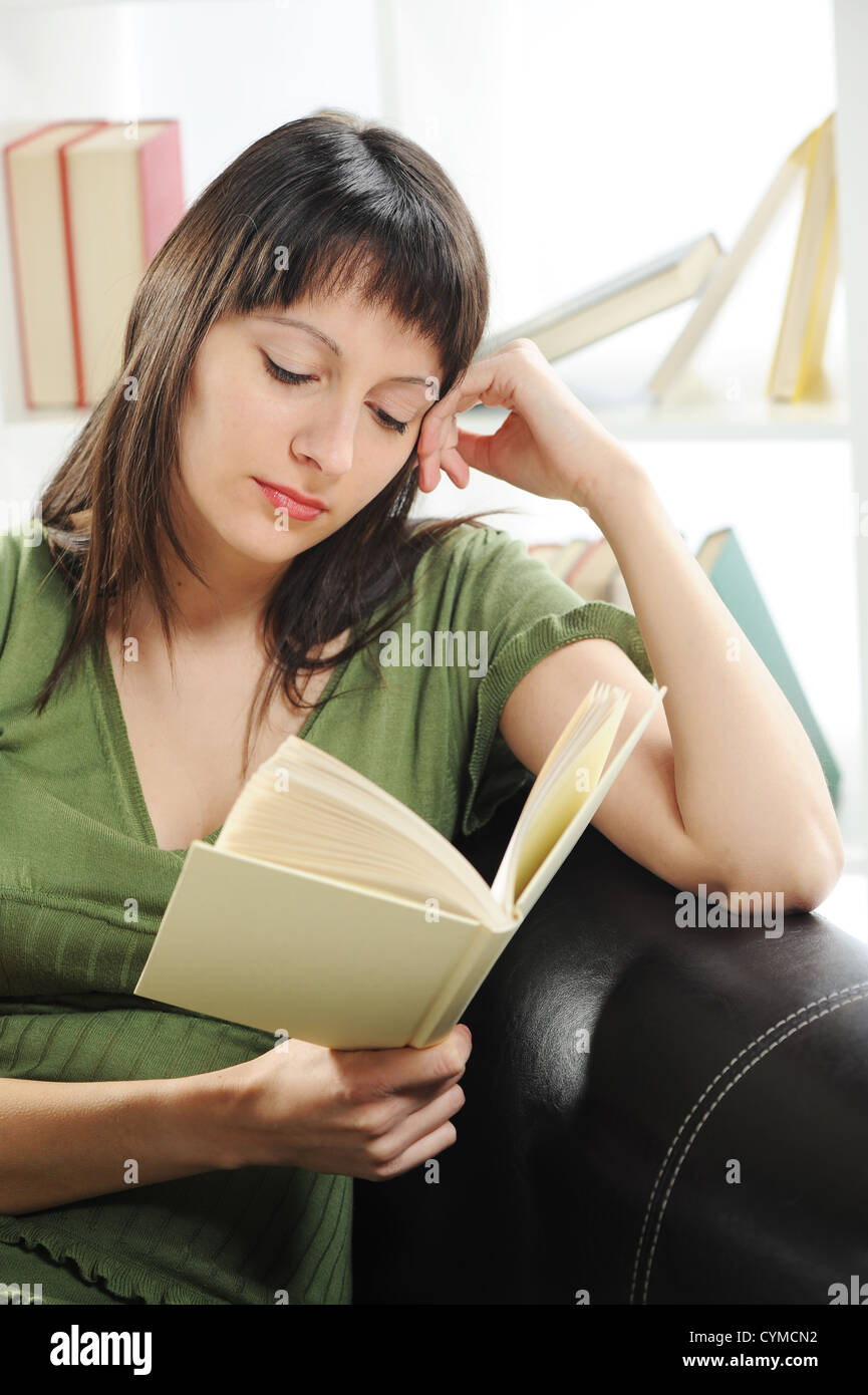 portrait of a young woman woman with book , bookshelf on background ...