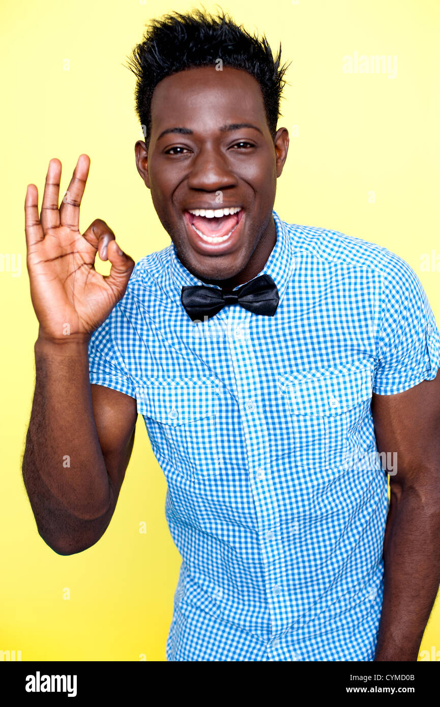 Joyful guy showing excellent gesture against yellow background Stock ...
