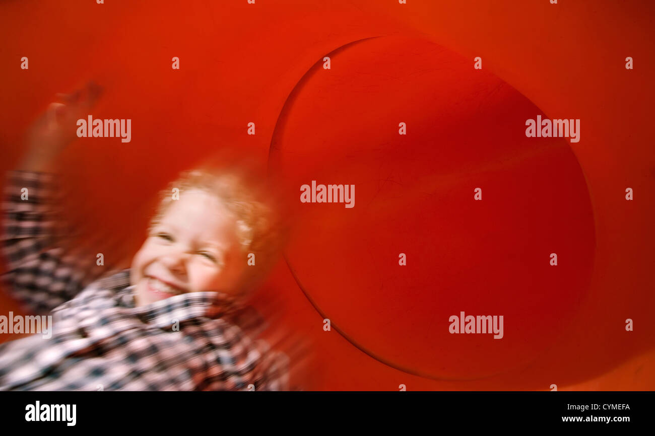 Boy slides down an red tube slide with motion blur Stock Photo - Alamy