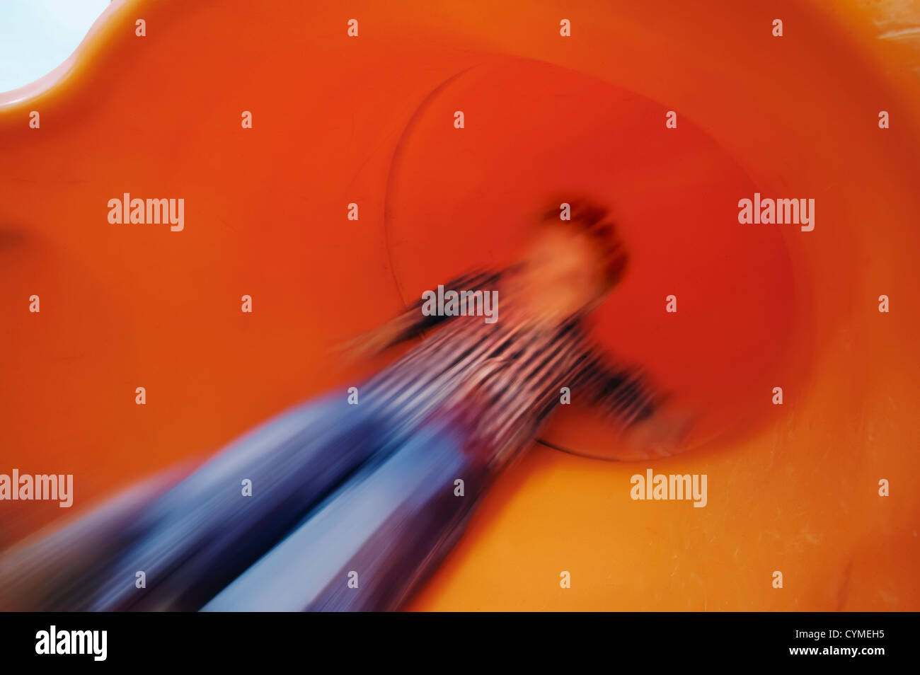 Boy slides down an orange tube slide with motion blur Stock Photo - Alamy