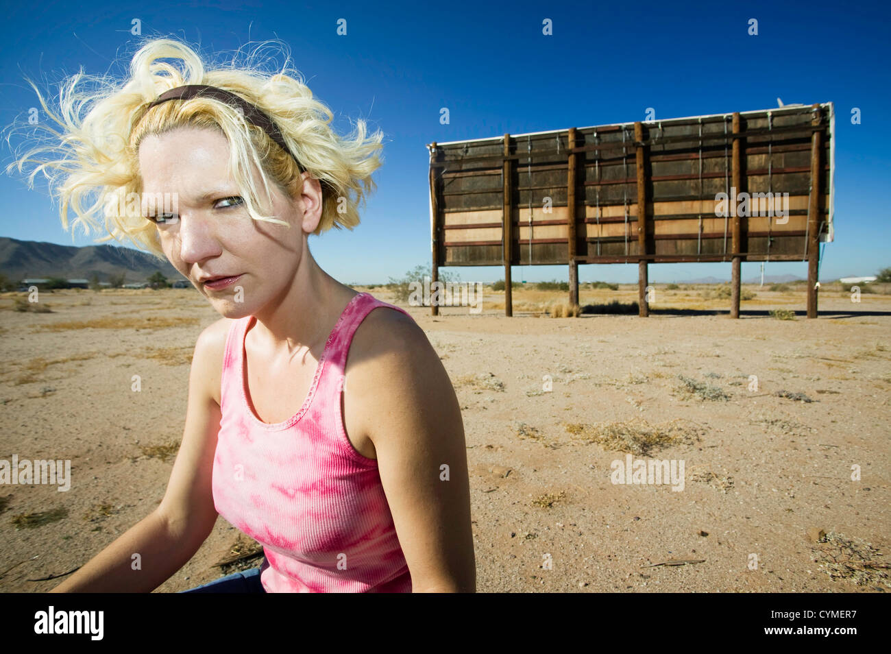 Woman with a sour expression in front of an old billboard waiting in ...