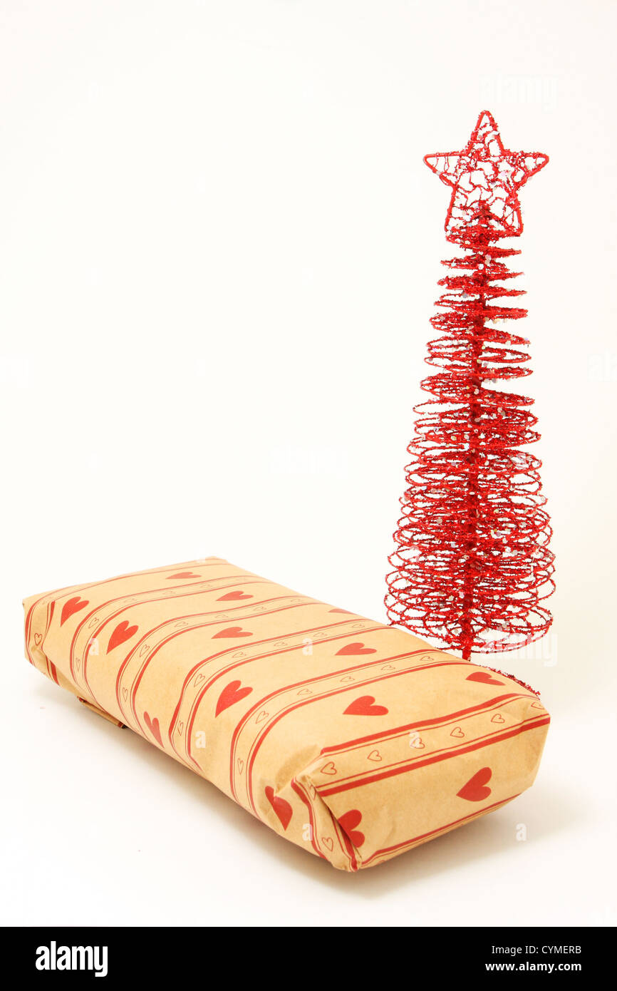 A wrapped present and red ornamental christmas tree shot on white ...