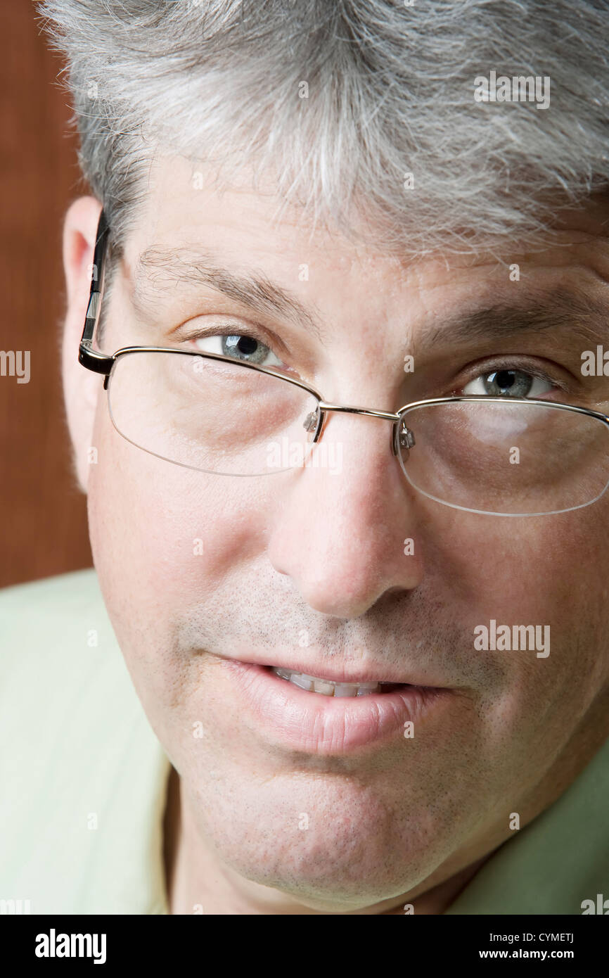 Man looking over glasses in front of a gold background Stock Photo - Alamy