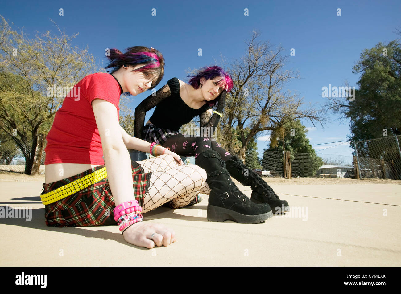 Two Punk Girls Sitting on a cement playground Stock Photo - Alamy