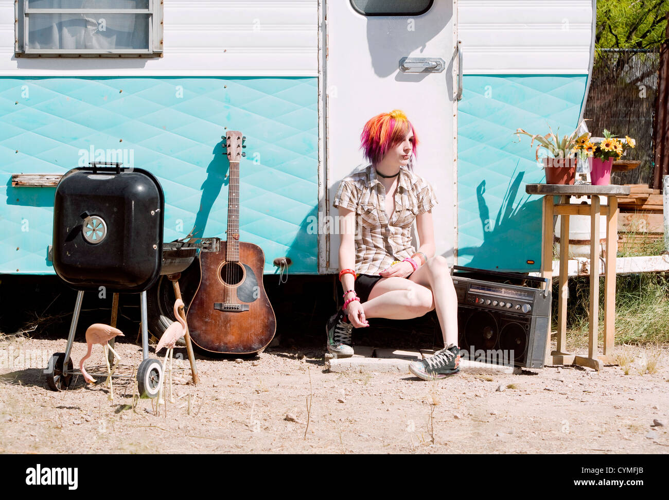 Punk girl with brightly colored hair sitting on a trailer step Stock ...