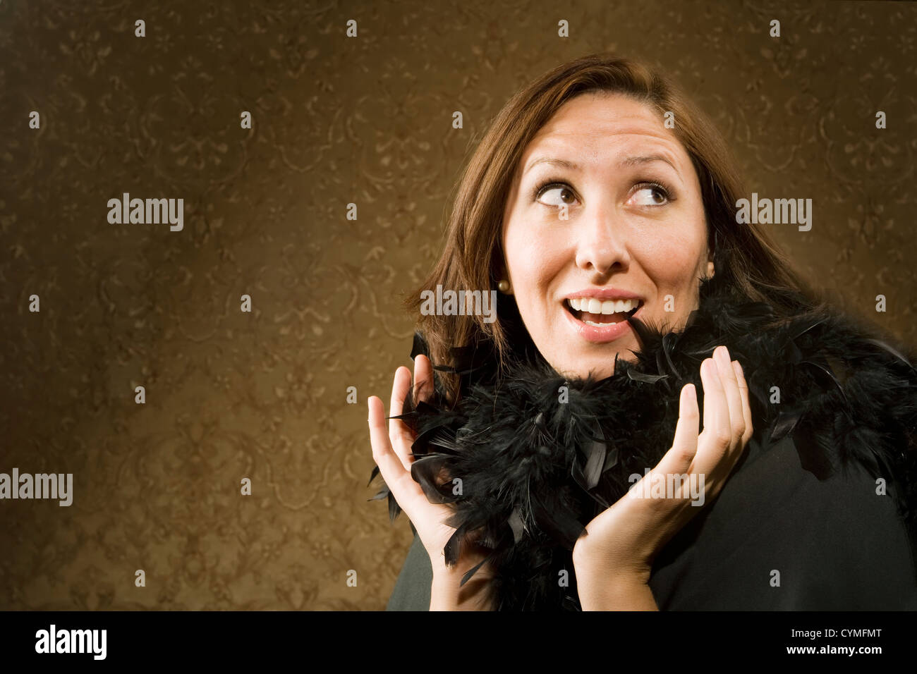 Pretty Hispanic Woman Wearing a Feather Boa in front of Gold Wallpaper ...