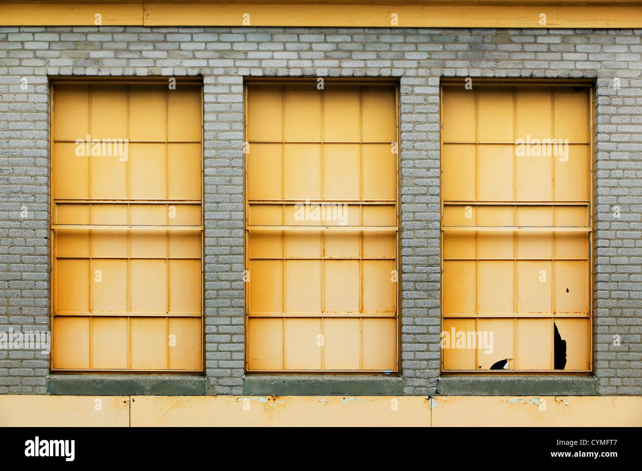 Three yellow windows on an industrial brick building Stock Photo - Alamy