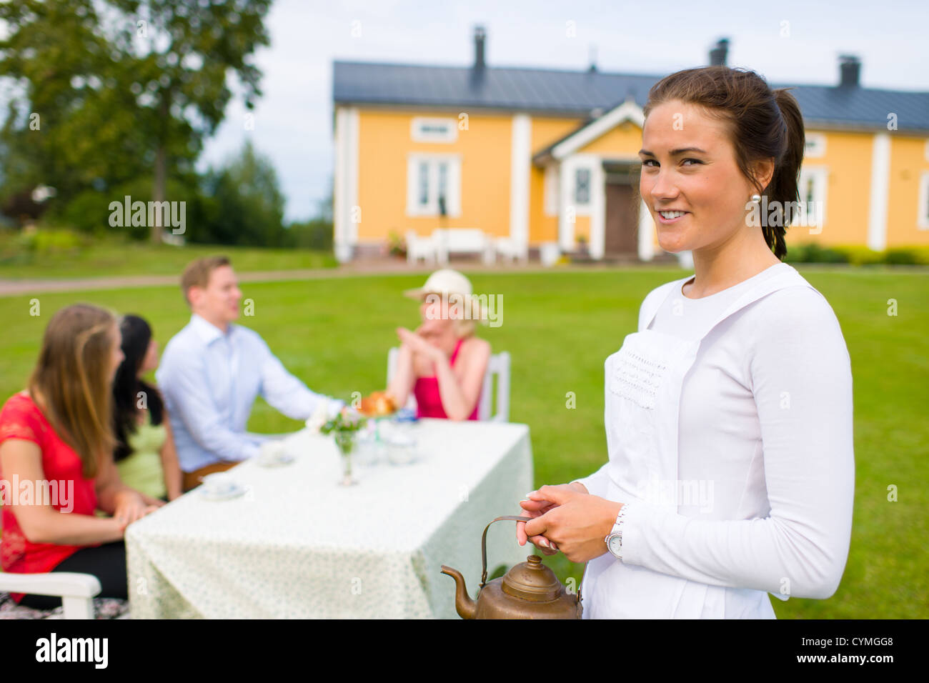 Smiling waitress standing front of customer group, who sitting on ...