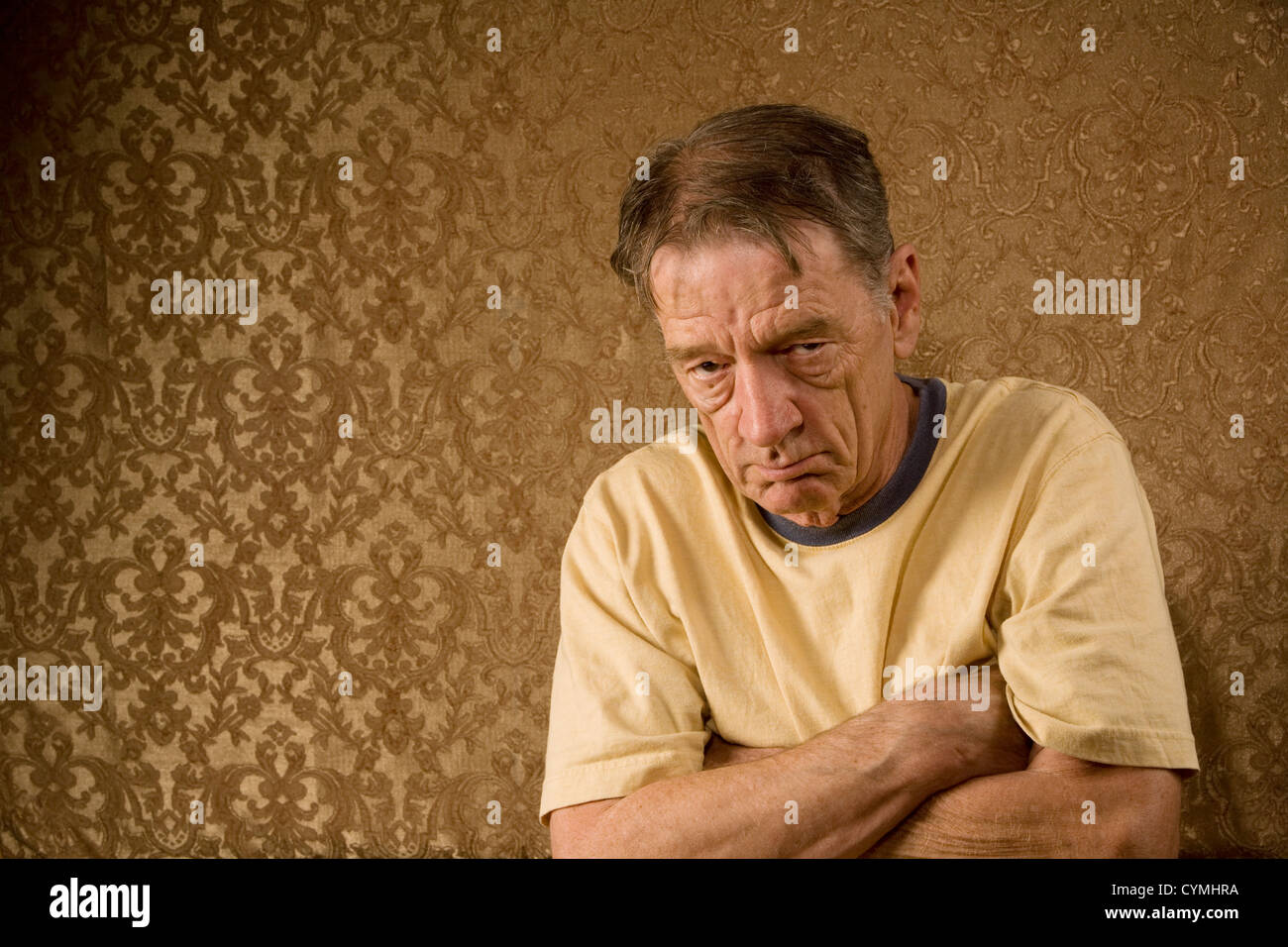 Senior Man Against a Gold Background with a Stern Expression and Arms ...