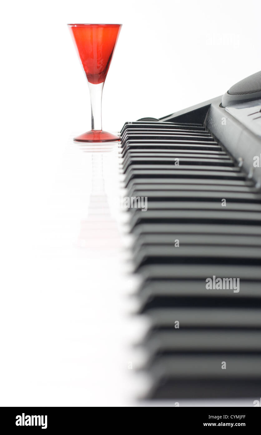 Piano keyboard and red glass on isolated background Stock Photo - Alamy