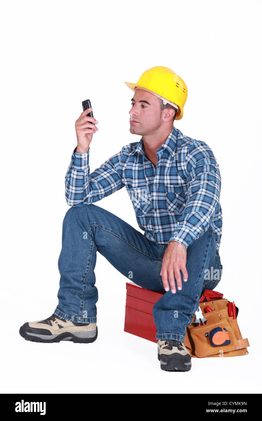 Man sat on tool box sending text message Stock Photo - Alamy
