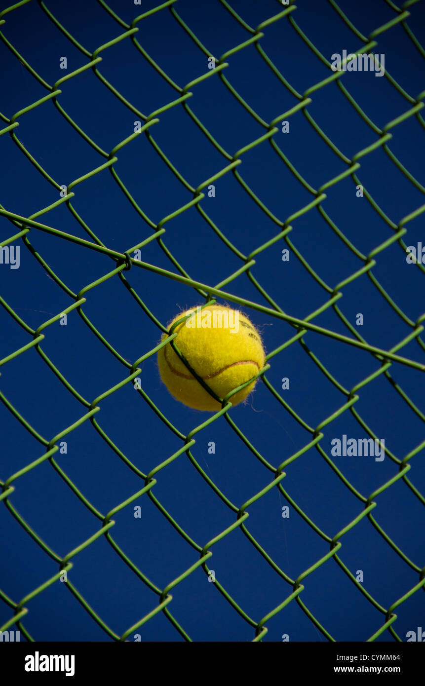 Yellow Tennis Ball Stuck In Green Fence Stock Photo - Alamy