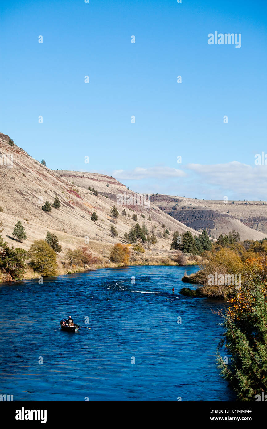 Two fisherman float down a river with mountains in the distance on a ...