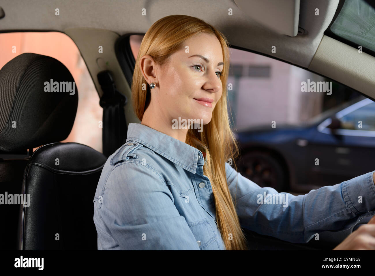 Beautiful young blond woman in car driving Stock Photo - Alamy