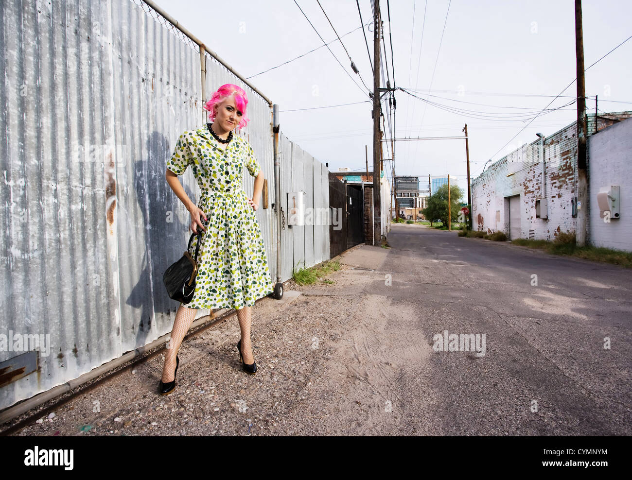 Woman with pink hair wearing polka dot dress in alley with purse Stock ...