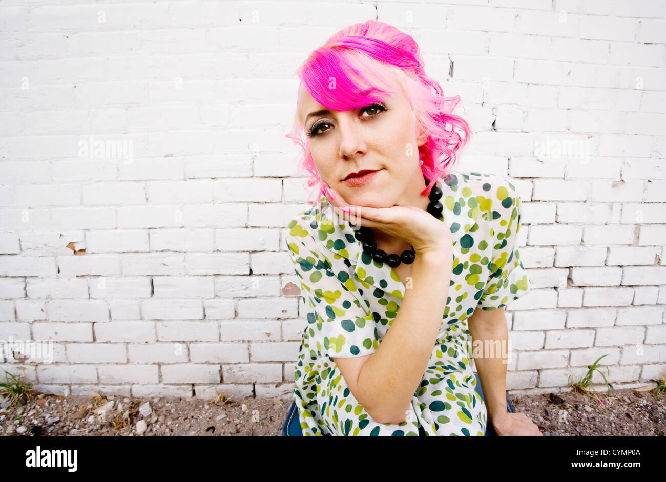 Woman with pink hair wearing polka dot dress in alley Stock Photo - Alamy