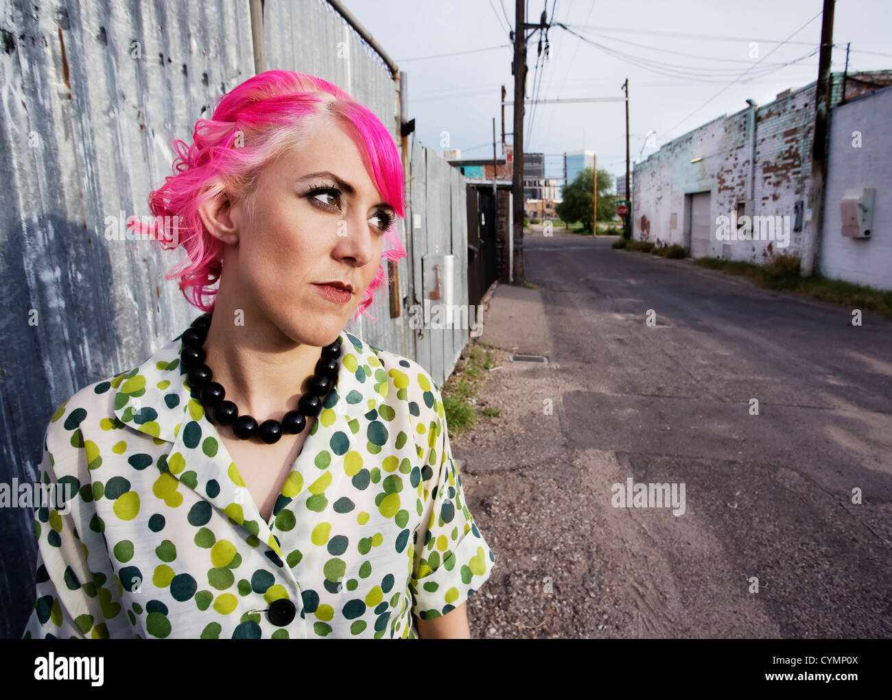 Woman with pink hair wearing polka dot dress in alley Stock Photo - Alamy