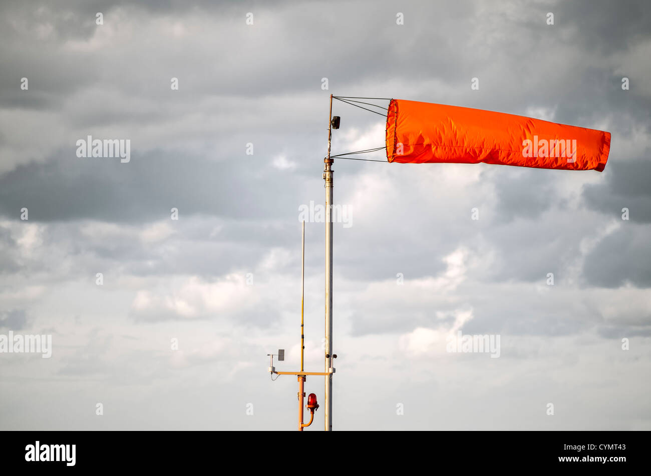 Gray steel sky before storm with fire-red air sock and signal light ...