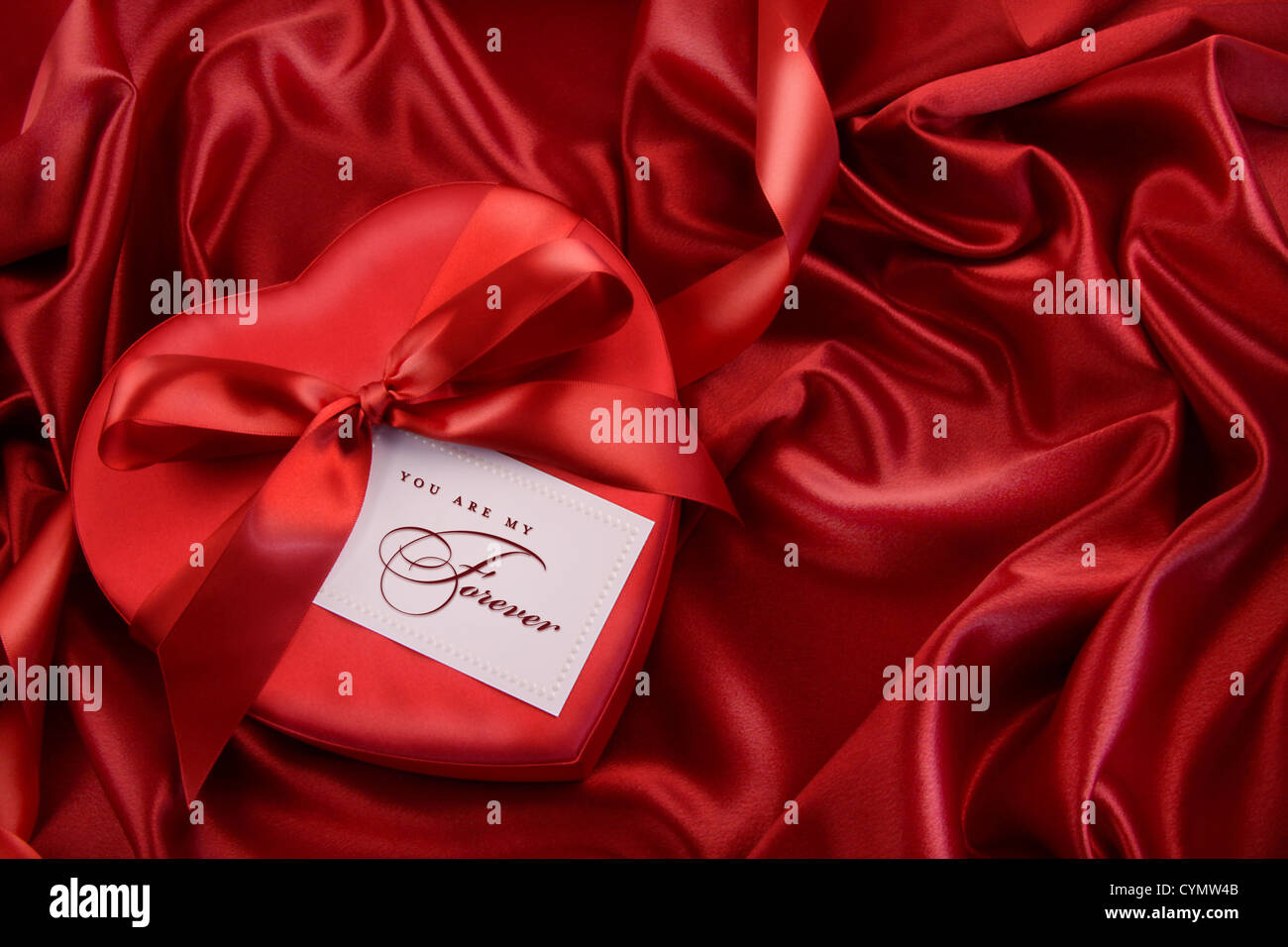 Box of chocolate with red ribbon on satin Stock Photo - Alamy