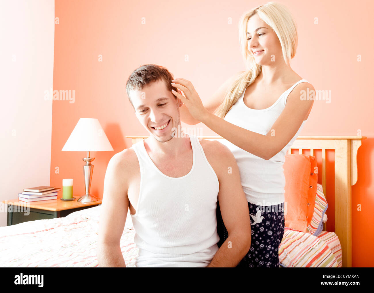 Woman ruffles man's hair as they relax in their bedroom. Horizontal ...