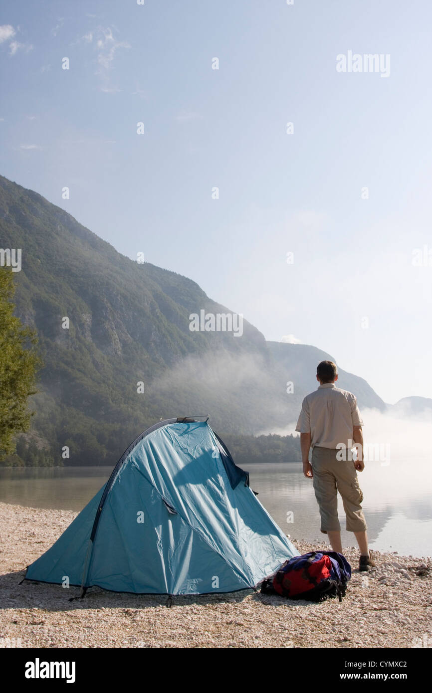Man standing beside his tent at mountain lake Stock Photo - Alamy