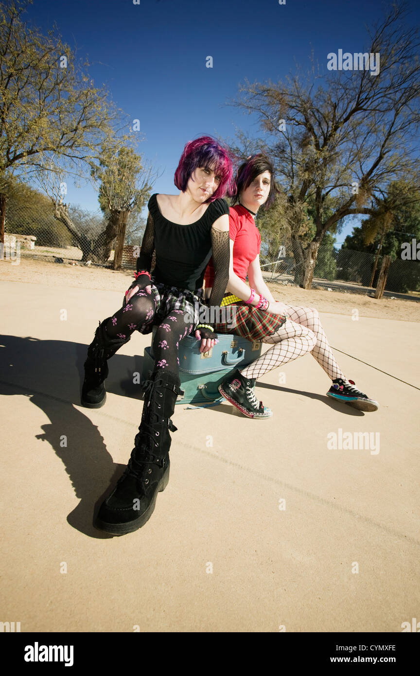 Two Punk Girls Sitting on Stacked Suitcases Stock Photo - Alamy