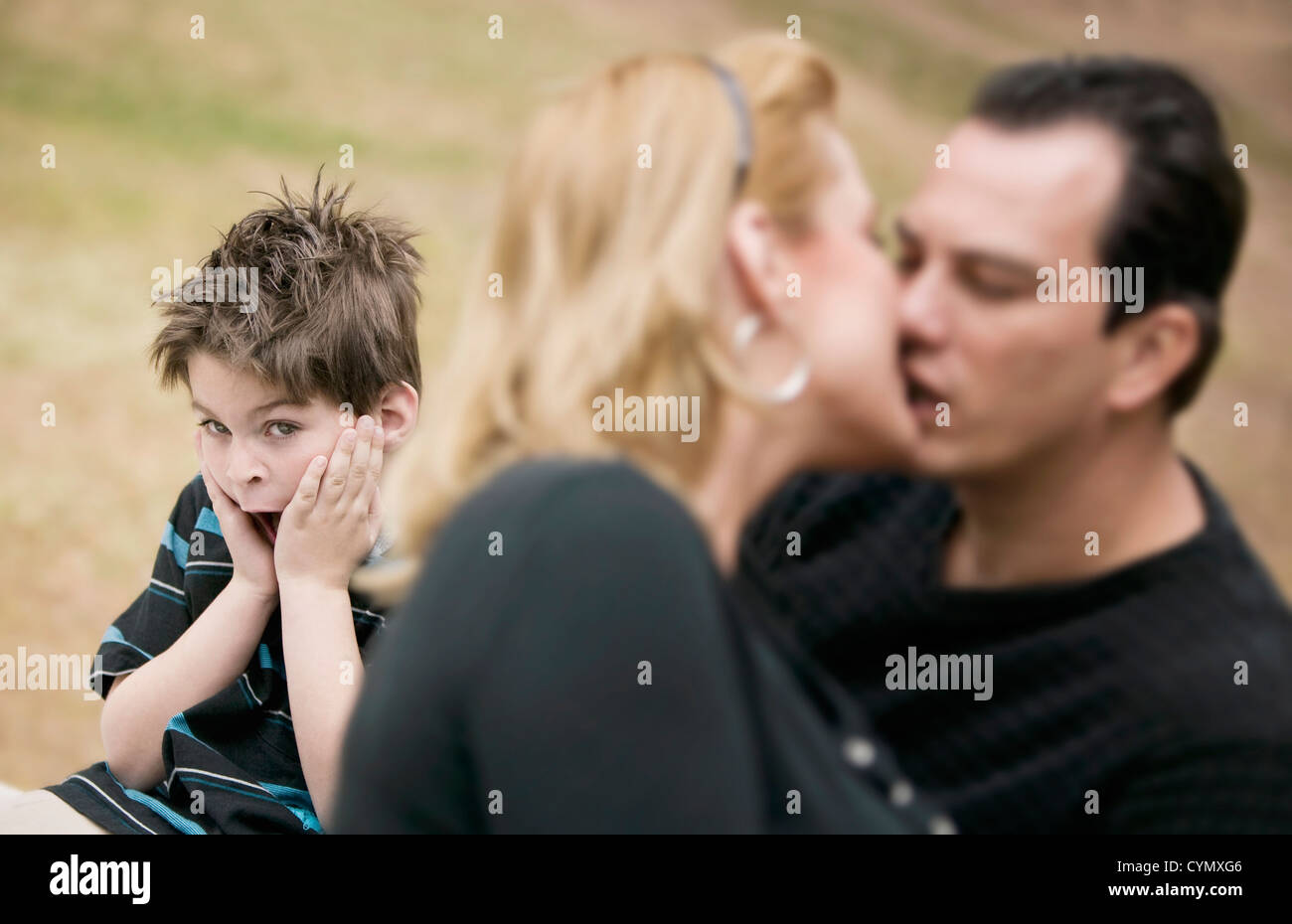 Horrified young boy with a kissing couple in the foreground Stock Photo ...