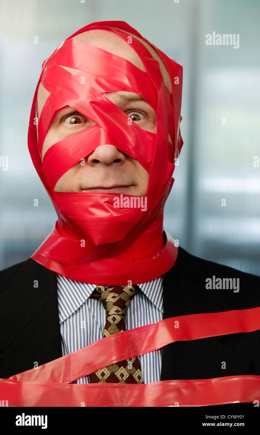 Businessman wrapped in red tape Stock Photo - Alamy