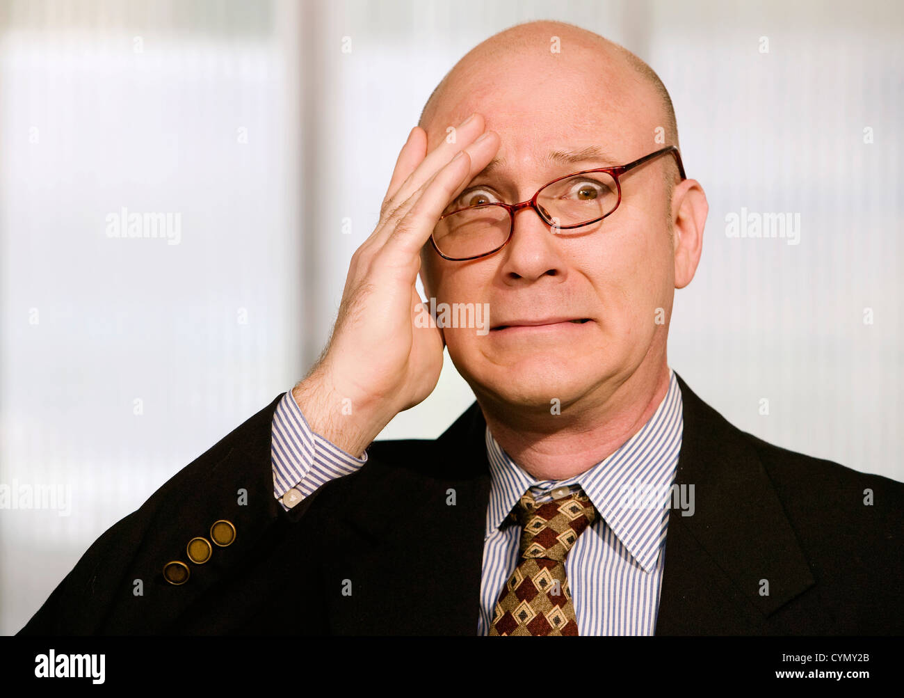 Frustrated businessman with his glasses askew and a hand to his ...