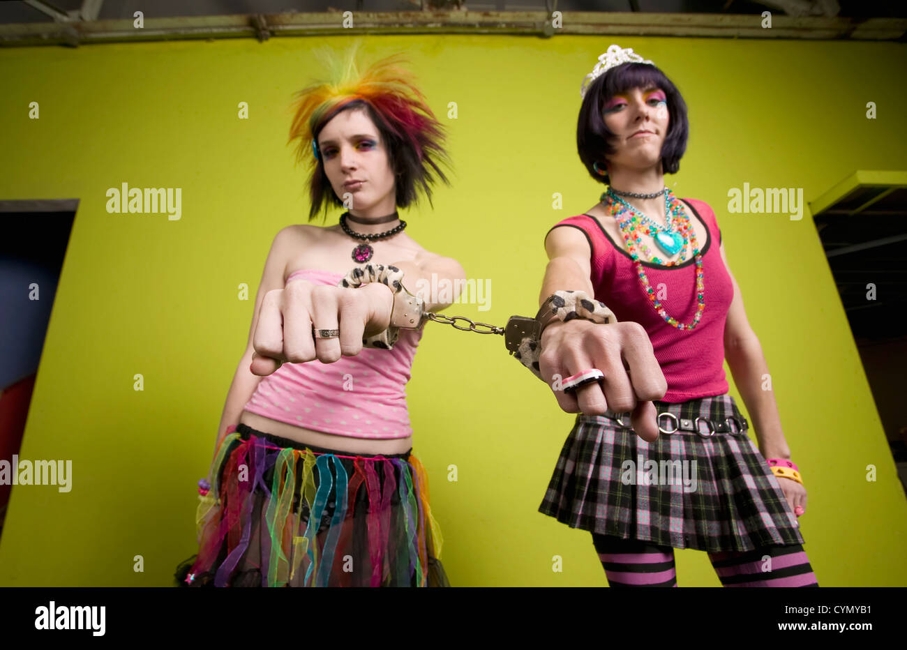 Wide angle of young punk women in front of a green wall linked by ...