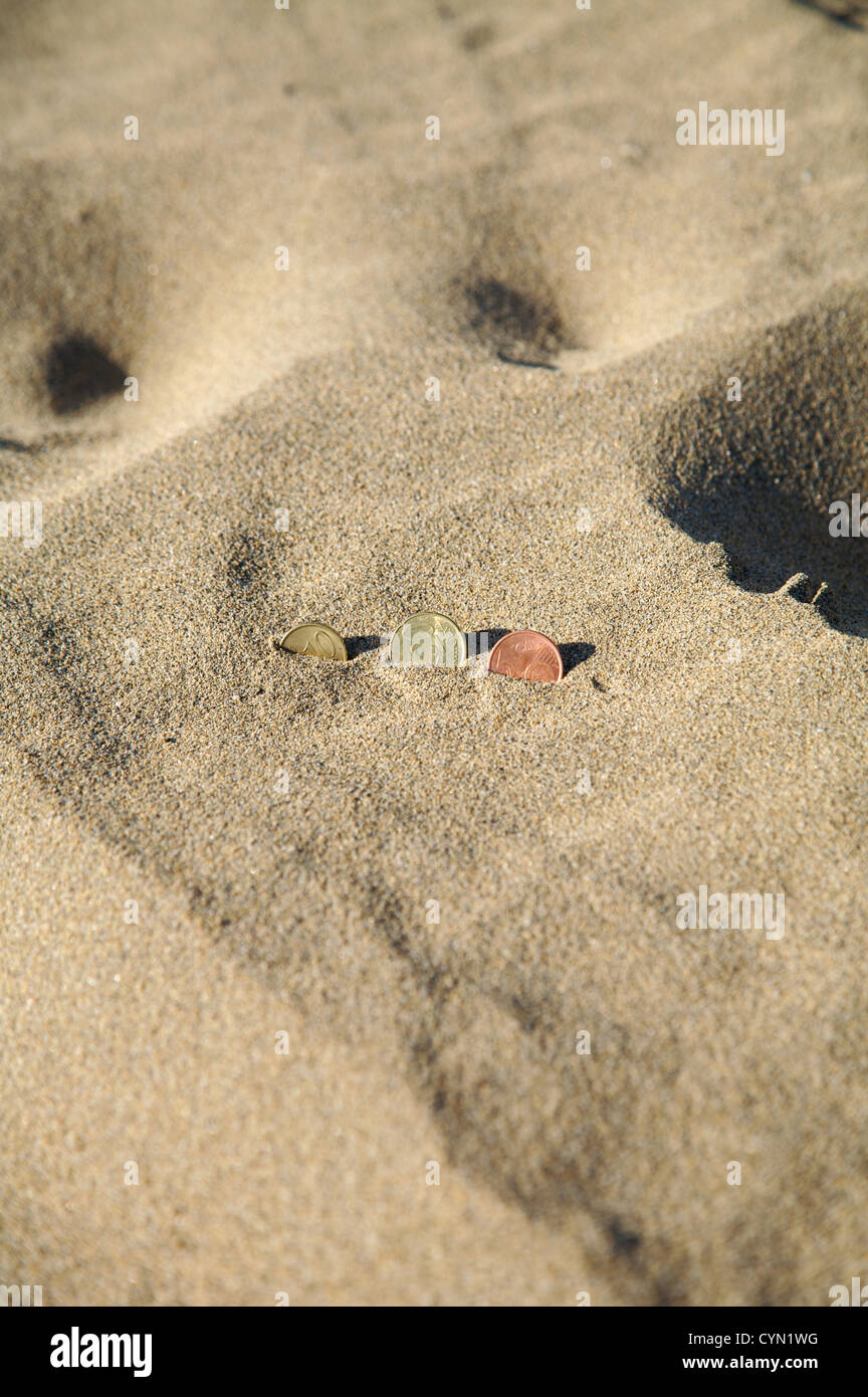 three euro coins at the sand of a beach Stock Photo - Alamy