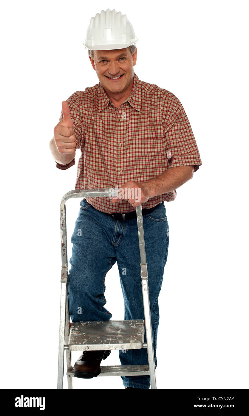 Experienced labor gesturing thumbs up to camera while climbing up on ...