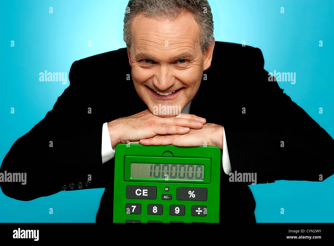 Aged corporate male resting face on big calculator looking at camera ...