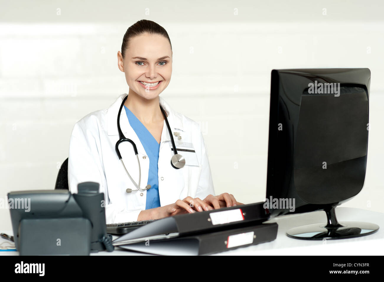 Smiling female doctor working on computer in her chamber Stock Photo ...