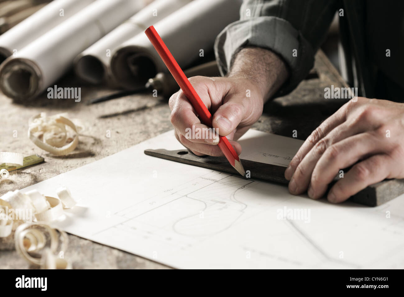 Closeup view of a carpenter using a red pencil to draw a line on a ...