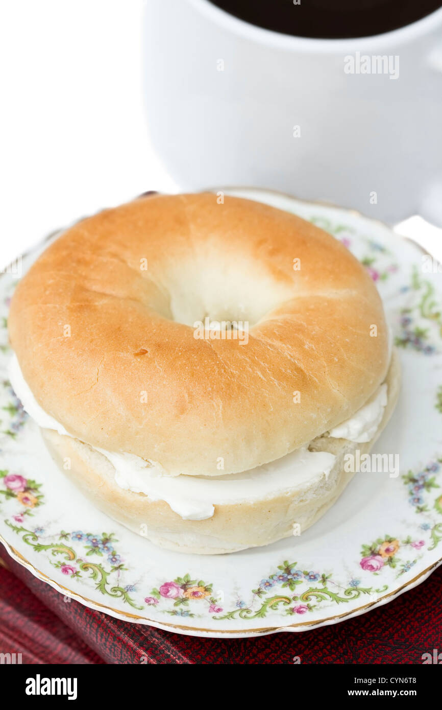 Bagel and coffee isolated on white. Bagel is sitting on top of old ...