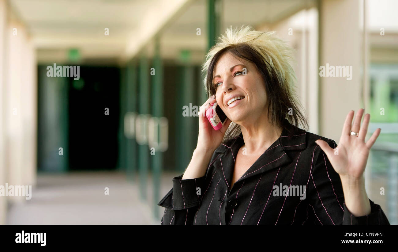 Modern businesswoman in an outdoor walkway talking on her cell phone ...