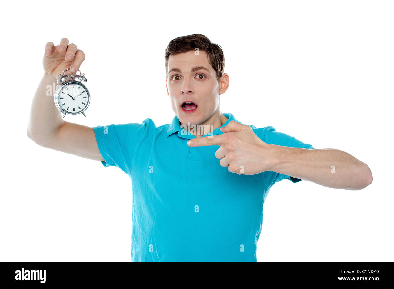 Shocked young guy holding alarm clock and pointing at it Stock Photo ...