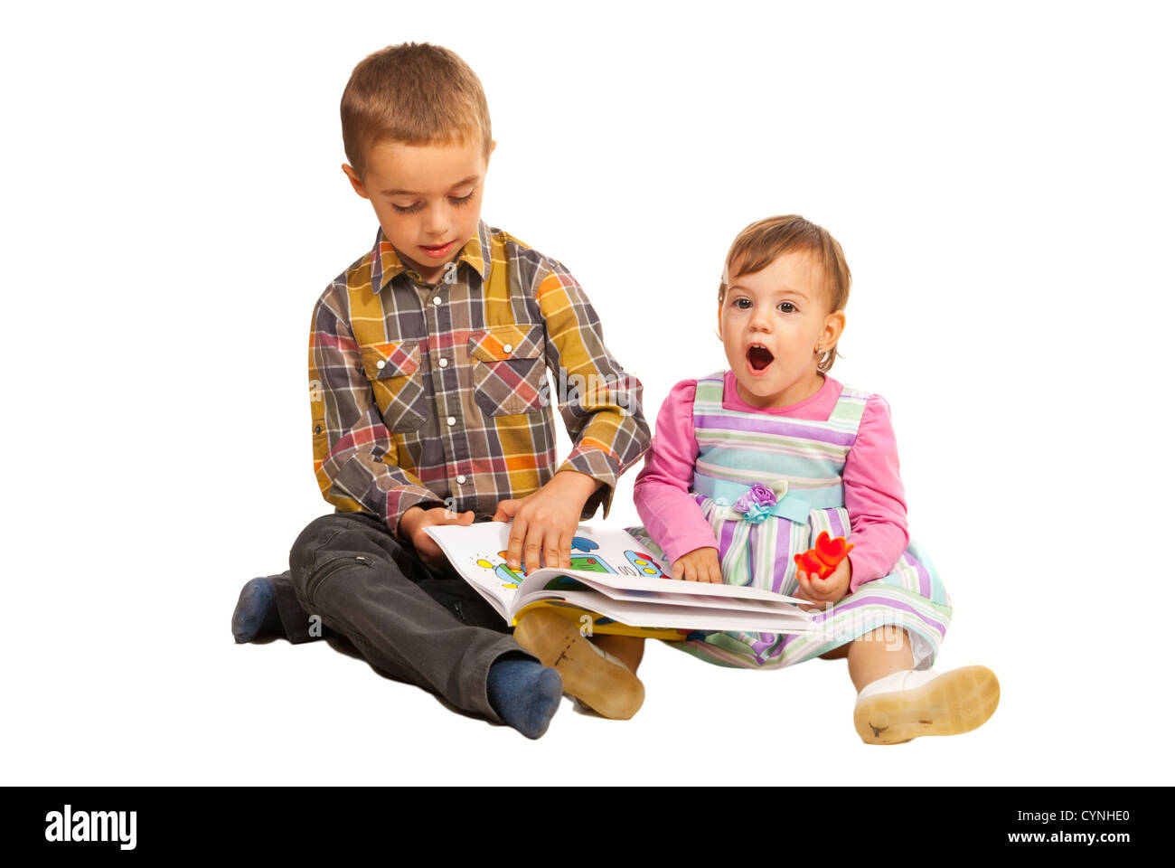 Amazed toddler girl by a story sitting on floor with her big brother ...